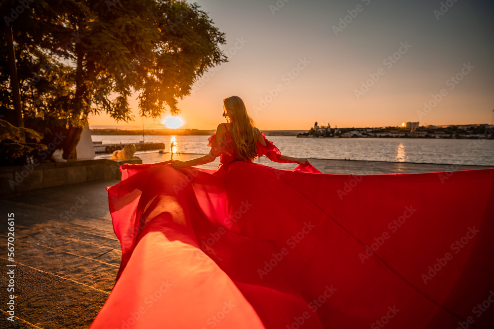 Sunrise red dress. A woman in a long red dress against the backdrop of ...
