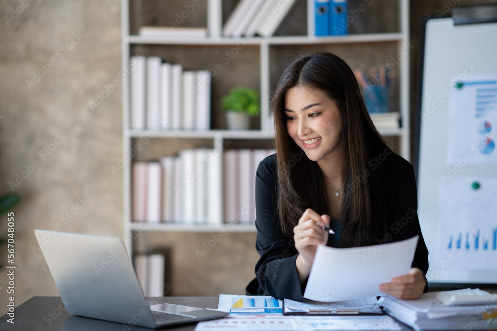 Young smart Asian businessworker working while holding company document ...