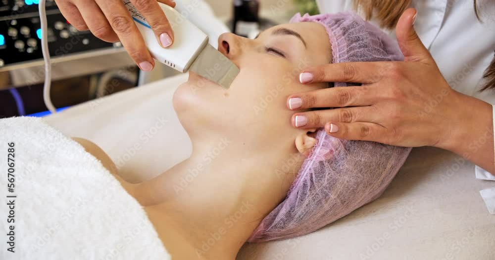 Beautiful woman receiving facial microcurrent treatment at spa salon. Beautician using ...