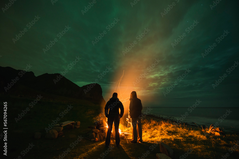 Standing around an campfire with northern lights - aurora borealis in ...