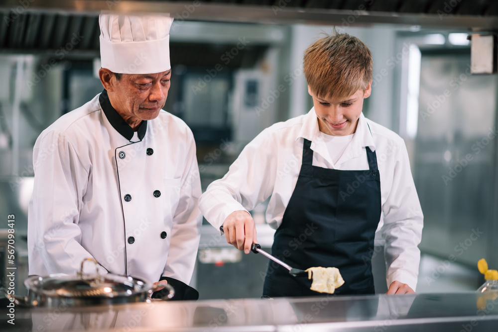 Mature asian teacher teaching schoolboy chef students to select ...