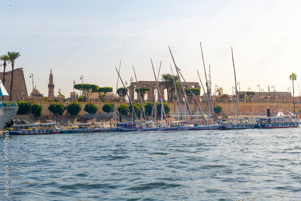 Colorful tour boats line the docks with the ancient Egyptian Luxor ...