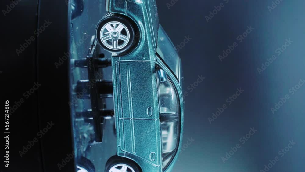 A tiny model metal sample car on a rotating stand with studio lights ...