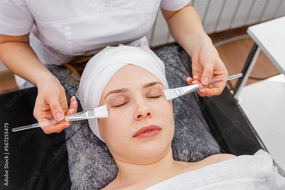 Beautician applying clay face mask on woman face. Cosmetologist ...