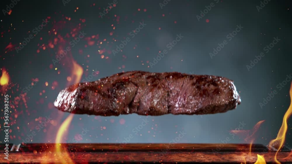Flying pieces of grilled beef steak falling on table. Filmed on high ...