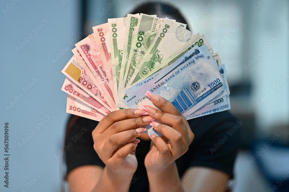 Nigerian woman covering her face with different denomination of the new ...