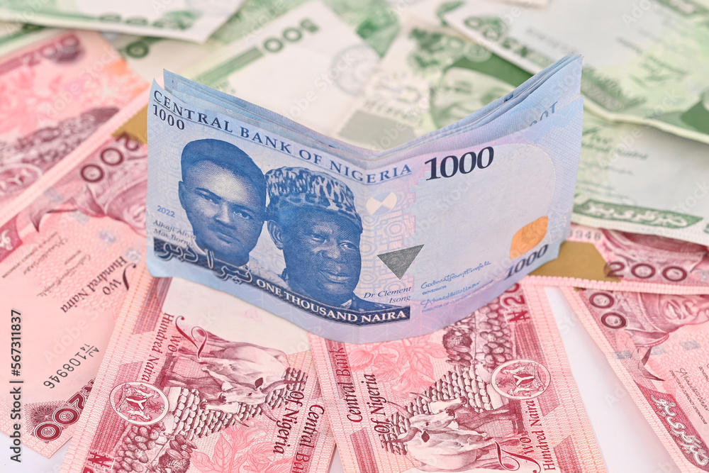 slightly bents 1000 new Nigerian Naira note on a pile of 500 and 200 ...