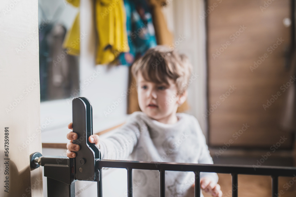 Foto de Toddler tries open lock on child safety gate. The child plays ...