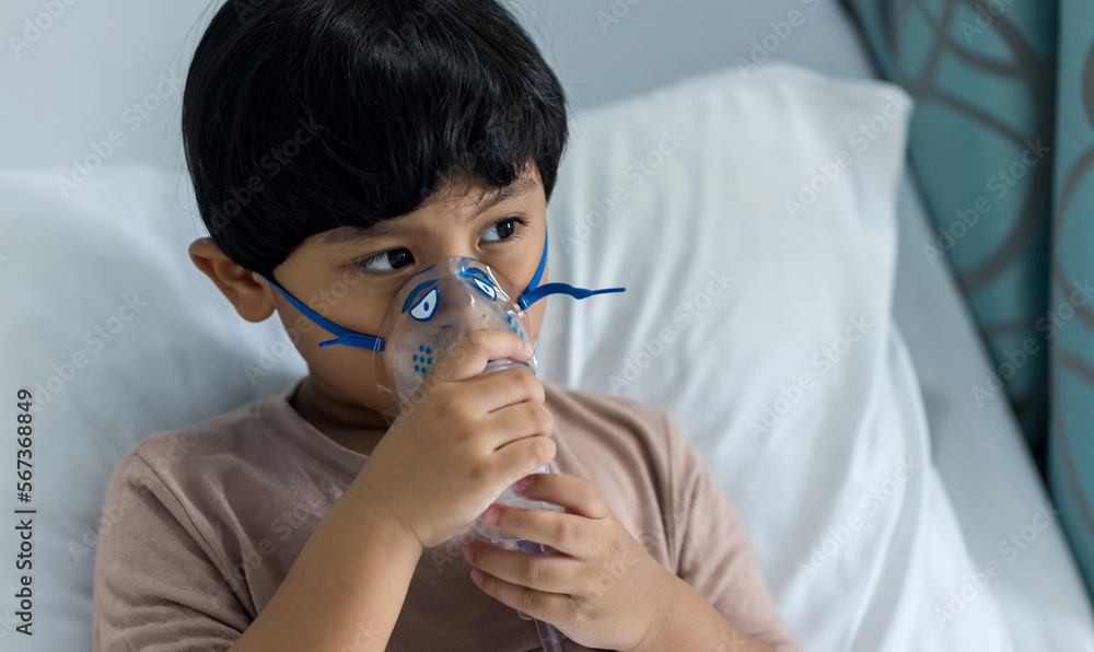 Sick boy inhalation therapy by the mask of inhaler. Baby has asthma and ...