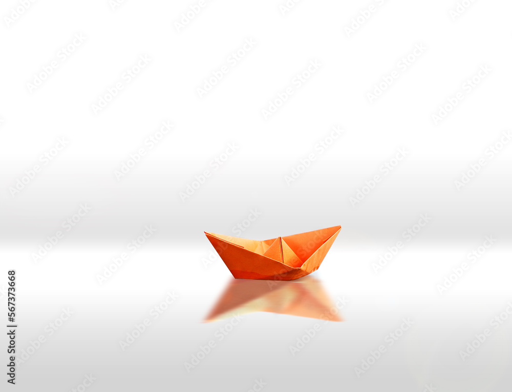 origami orange paper boat sailing on water causing waves and ripples ...