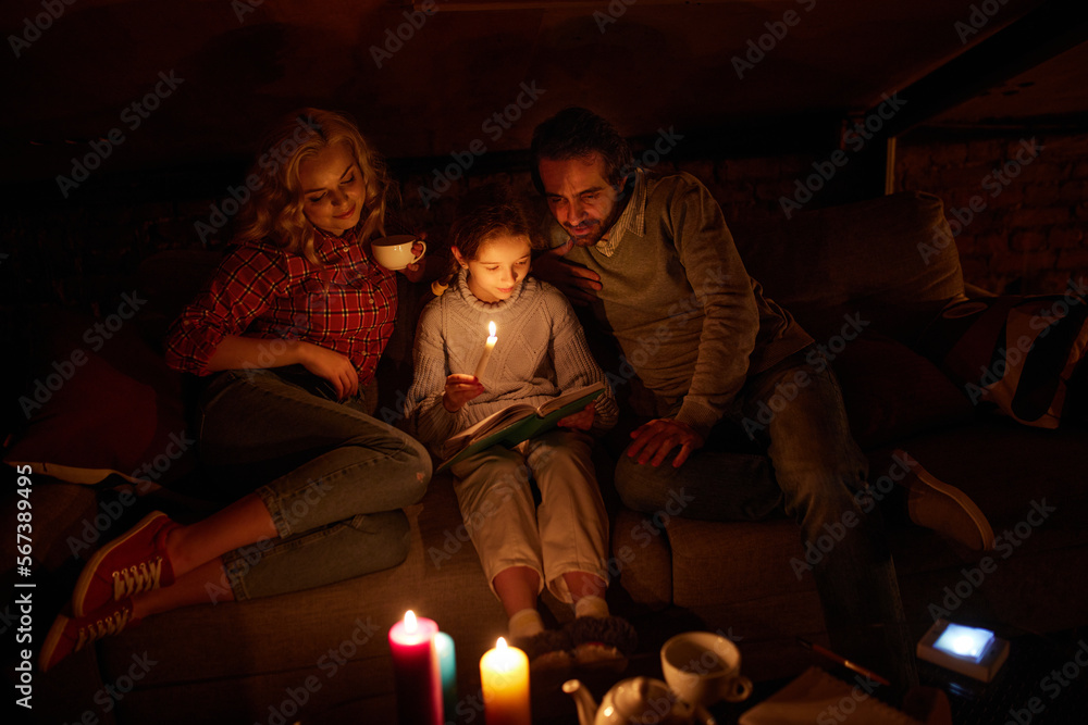 Cozy family evening. Mother, father and little girl sitting on sofa ...