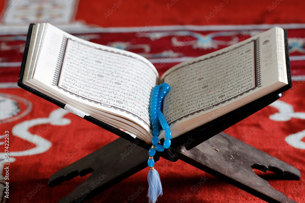 Open Quran and Muslim prayer beads on wood stand, symbol of Islam, An ...