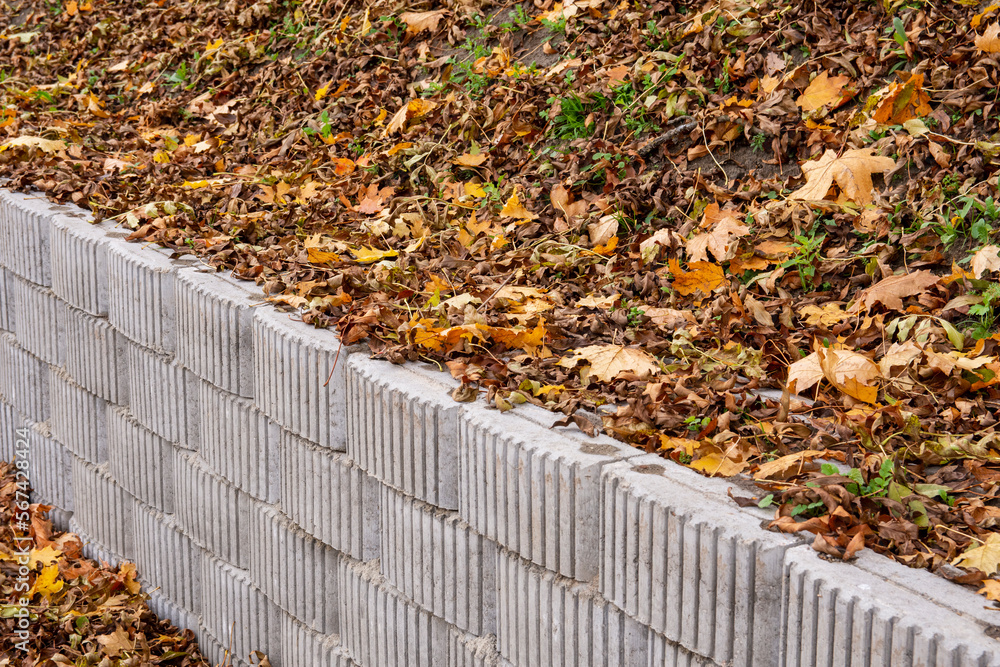 A retaining wall made of concrete elements protects the roadway and ...