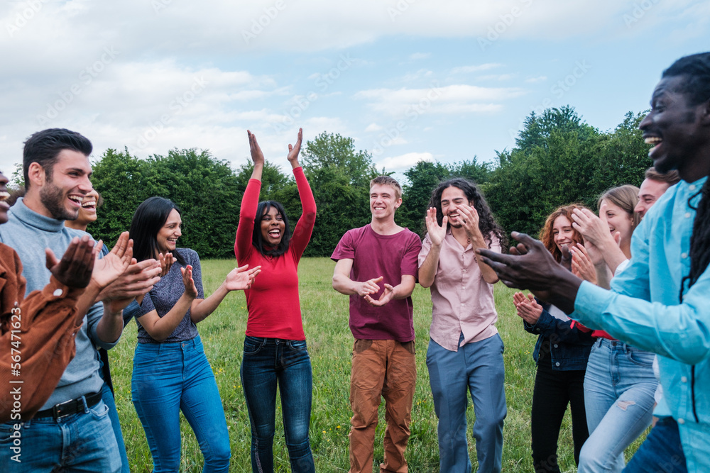 Heterogeneous group of young people from diverse backgrounds clapping ...
