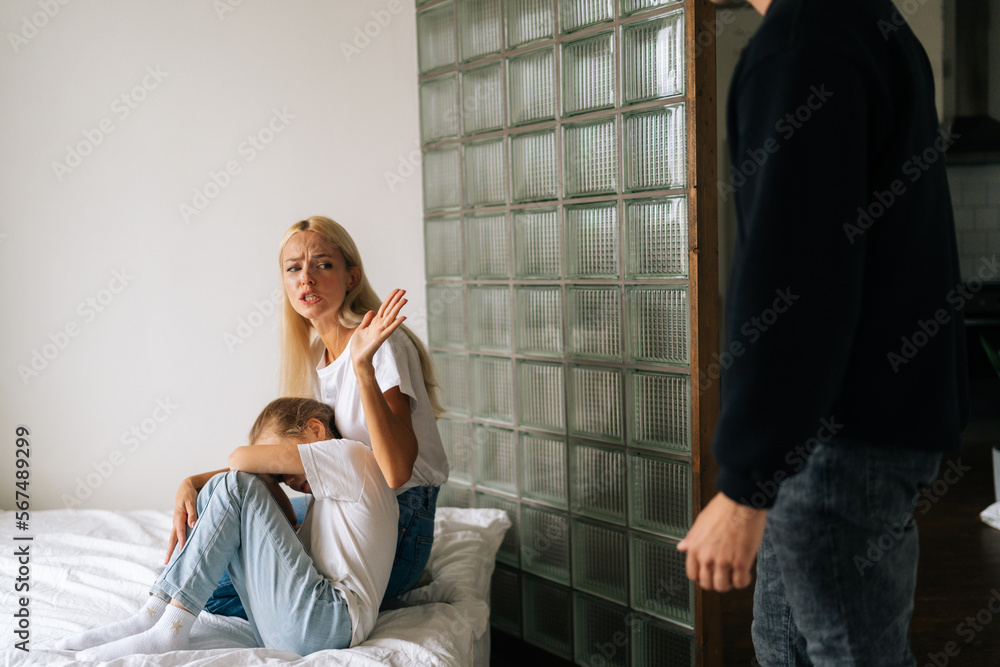 Portrait of scared mother and daughter hugging each other sitting on ...