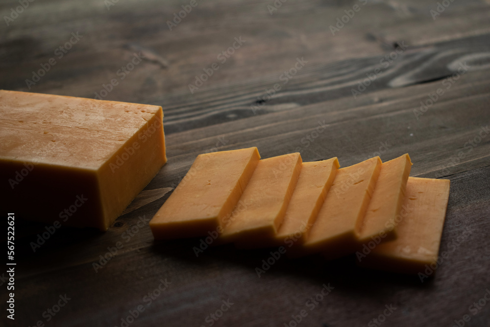 Close up block and cheddar and slices of cheese on rustic background ...