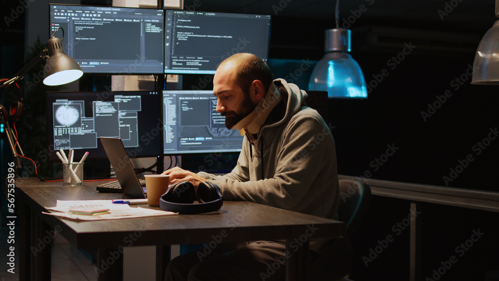 Software engineer wearing cervical collar at office, typing server code ...