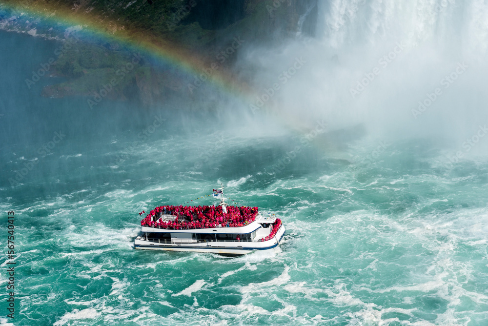 A rainbow guides a tour boat as it plies the turbulent water of the ...