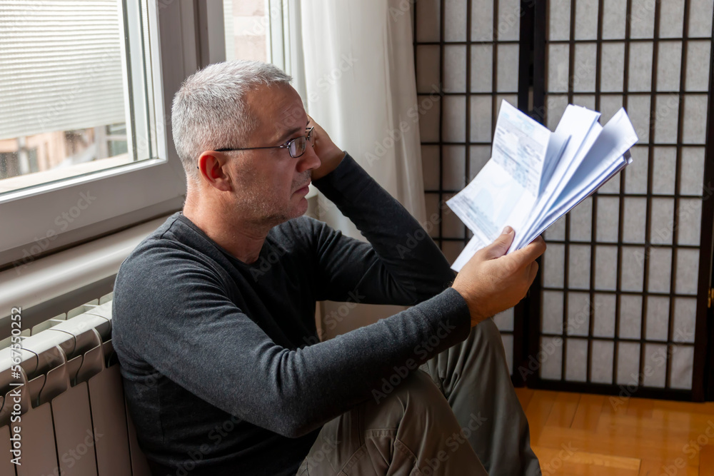 Stressed man looking at the high electricity bill because of the heat ...