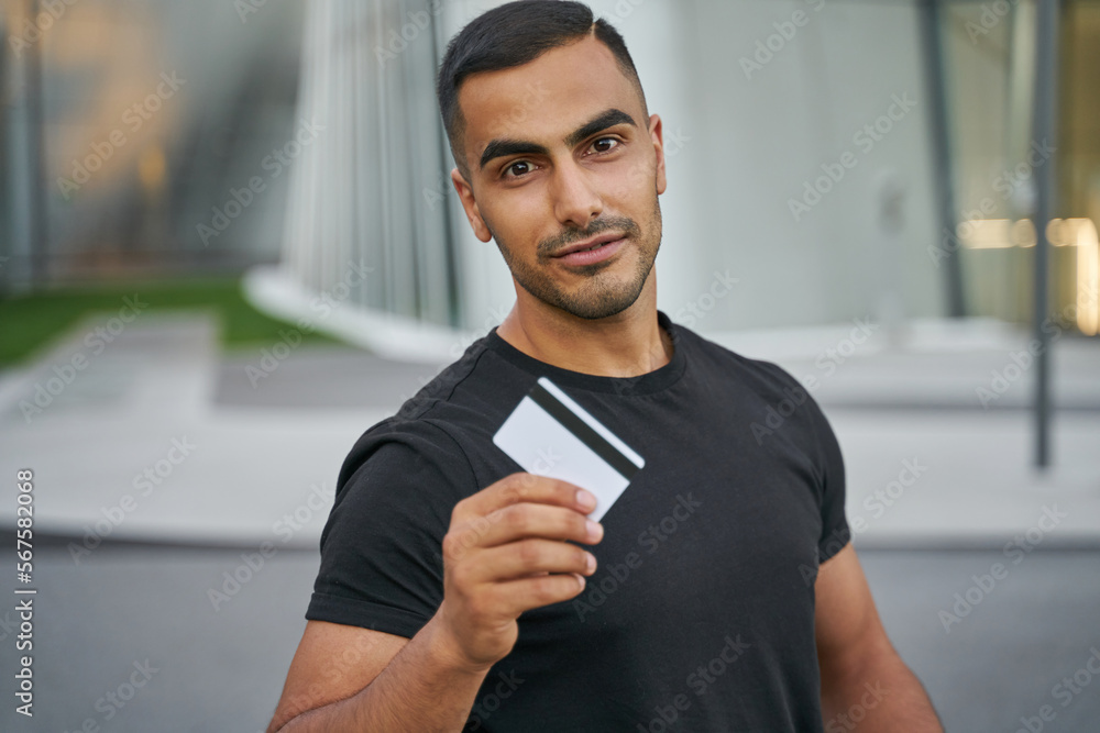 Handsome smiling middle eastern man holding credit card looking at ...