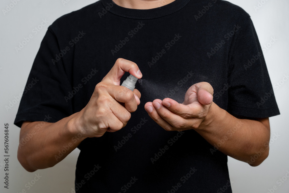 Asian man applying alcohol spray hand sanitiser to his hand to prevent ...