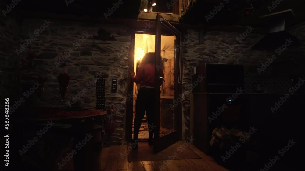 Woman walking to the door and checking if someone is there at night ...