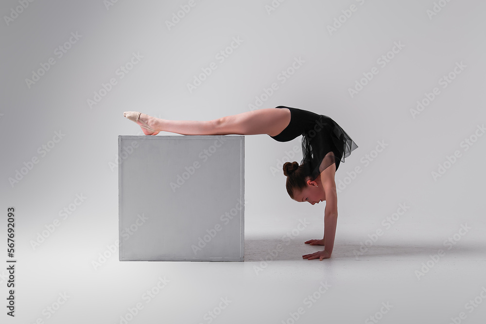 A flexible sports girl gymnast in a black gymnastic bodysuit performs a ...
