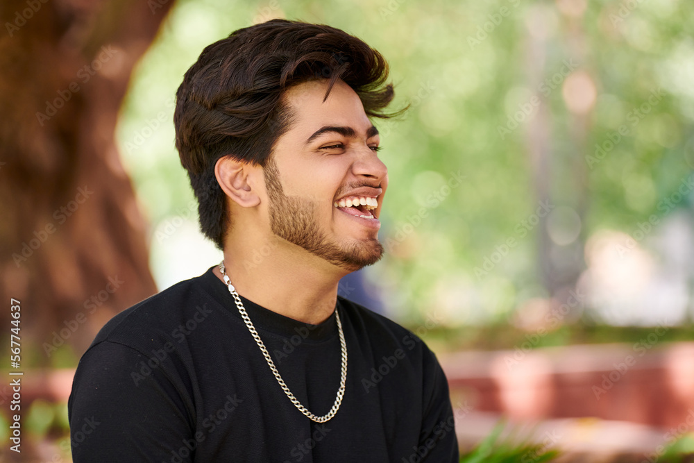 Smiling young indian man candid portrait in black t shirt and silver ...