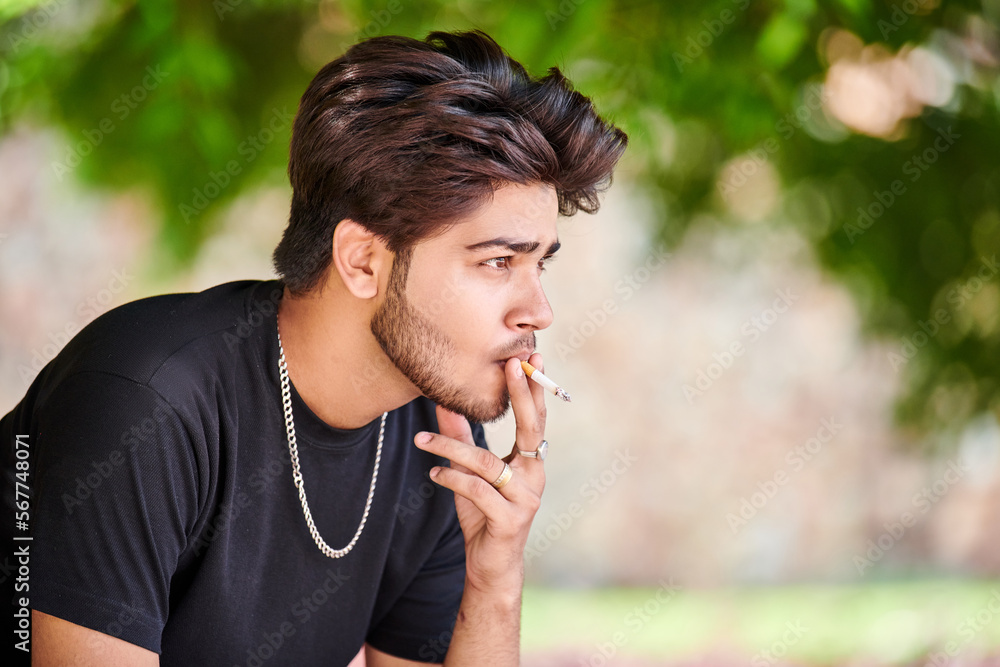 Young indian man smoker portrait in black t shirt and silver neck chain ...