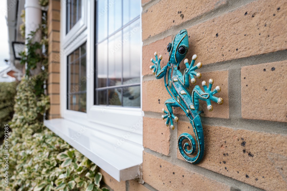 Ornate, metal lizard seen on a rear wall of a house. The leaded, double ...