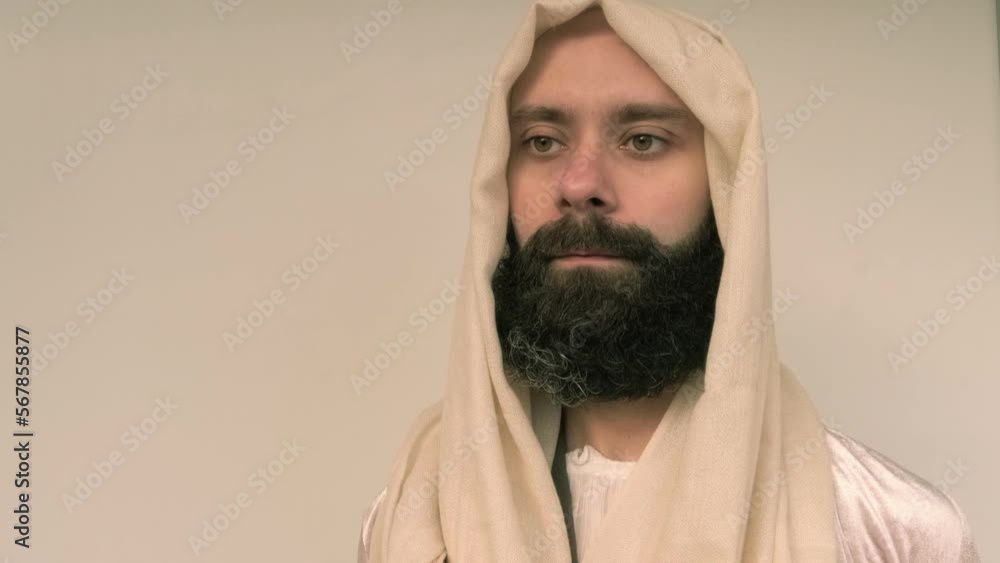 close-up male face in beige head cape, young pensive bearded man in ...