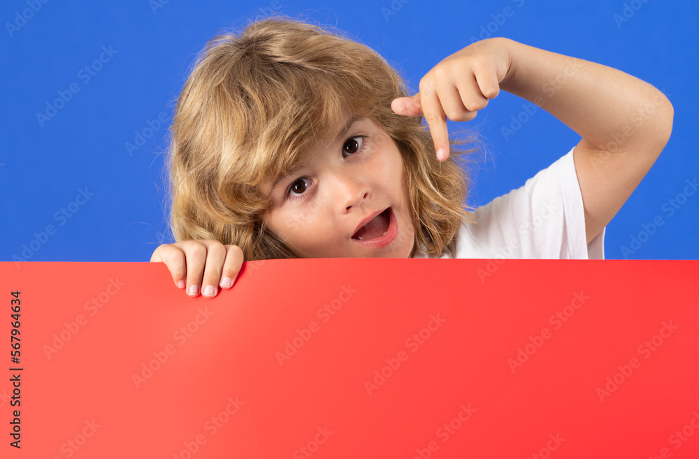 Excited child pointing on blank banner on studio background ...