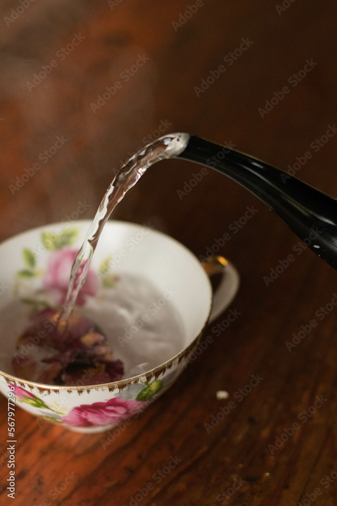 black kettle tipping boiled water into tea cup Stock Photo | Adobe Stock