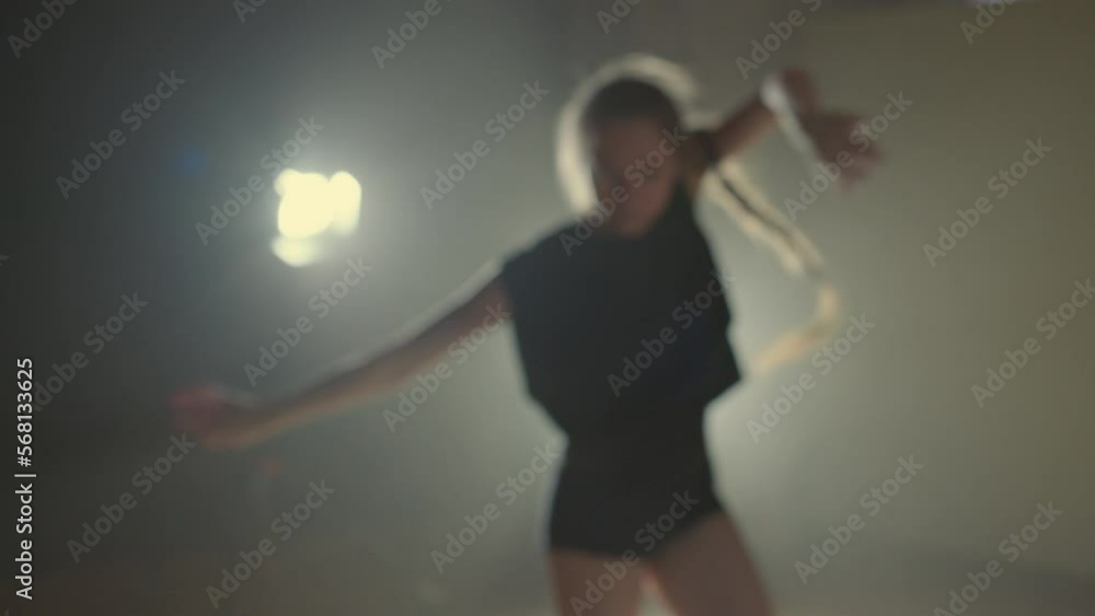 Blurred silhouette of dancing woman. Sporty girl with long braid moving ...