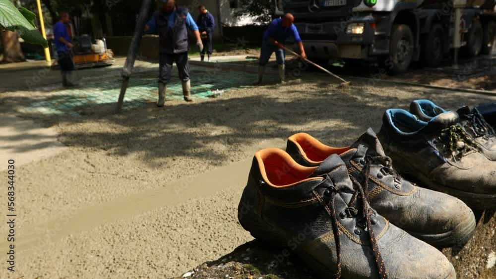Old worn out safety shoes lined, placed on small wall near construction ...