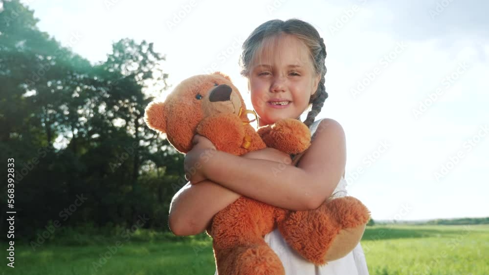 little kid girl hugging a teddy bear toy portrait in the park in nature ...