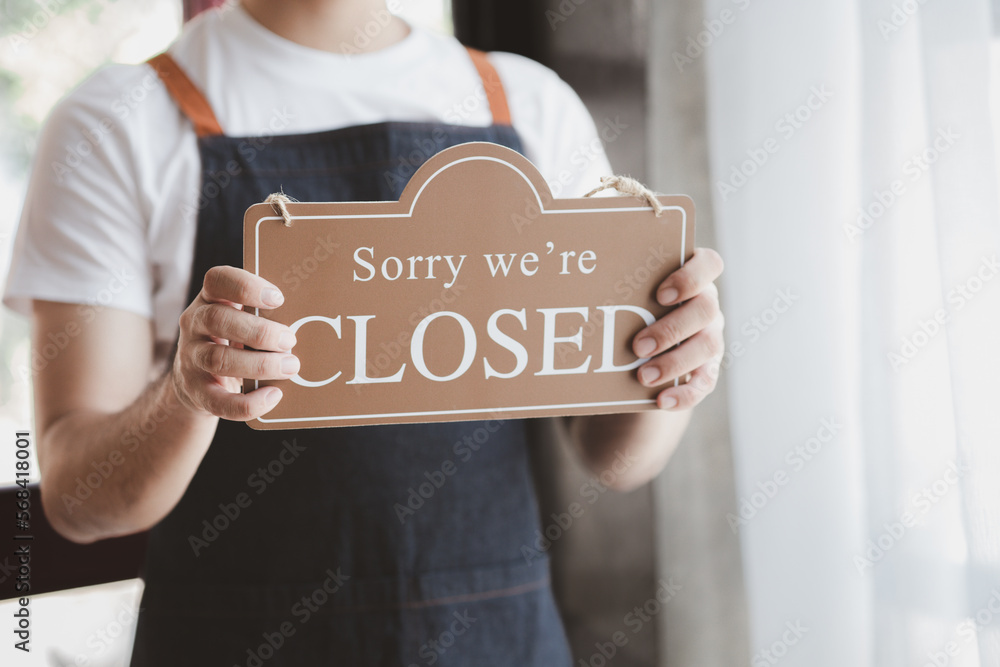 Man holding open/close sign in front of entrance, Goods and Service ...