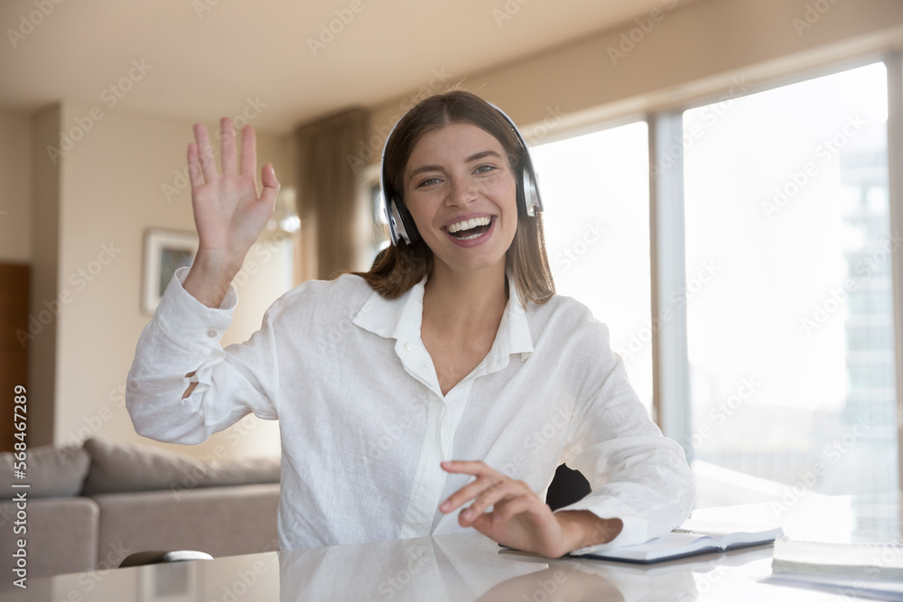 Happy excited millennial gadget user girl in big earphones waving ...