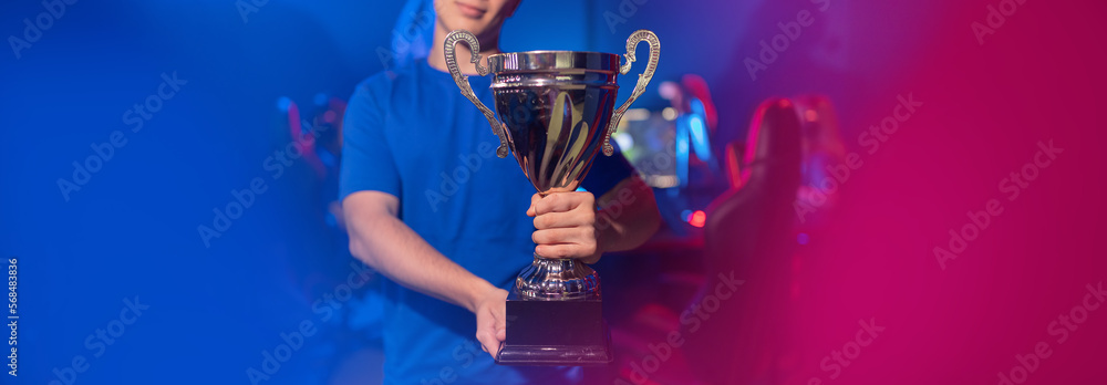 Concept banner cyber gaming esport. Winner gamer young man holding cup ...