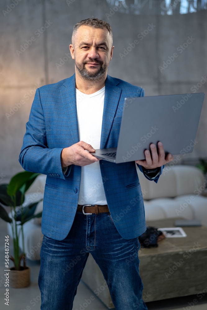 Bearded young confident guy stand behind office desk with laptop ...