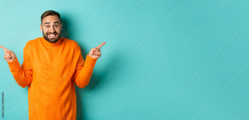 Confused handsome man shrugging indecisive, pointing fingers sideways ...