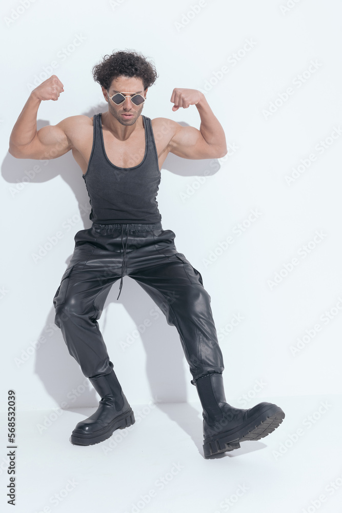 sexy muscle man with curly hair wearing leather pants and flexing ...