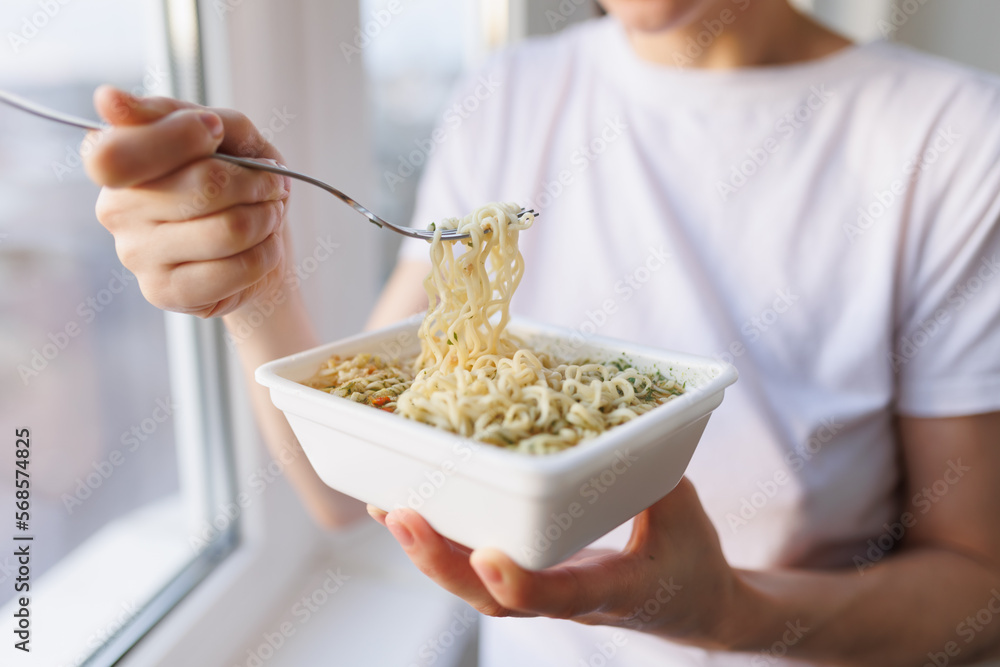 A image of someone eating instant noodles at home by the window in the ...