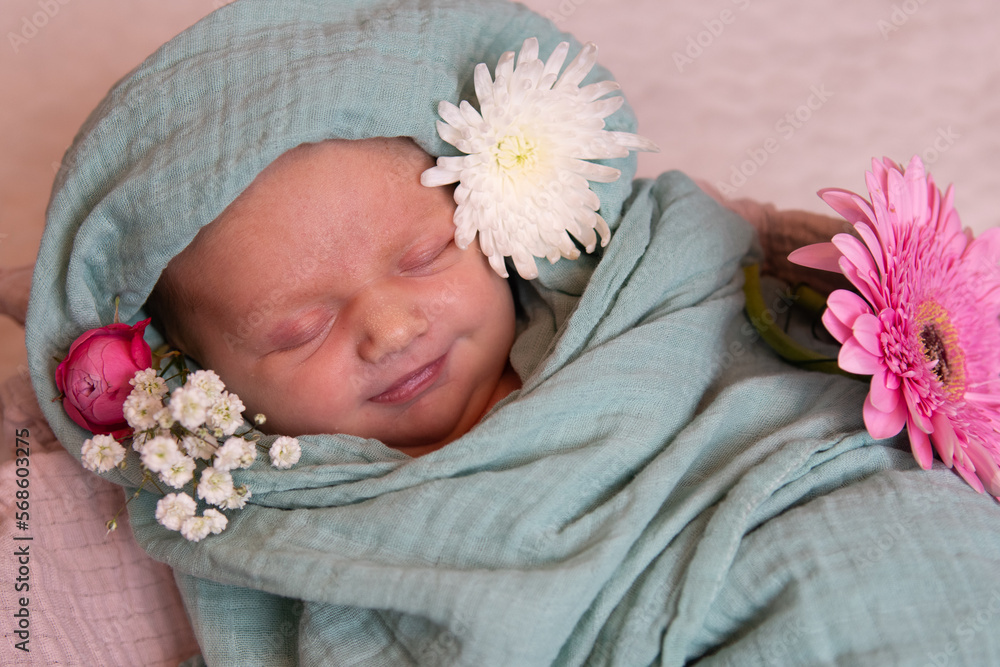 Newborn baby girl 6 days old sleeping with a smile and flowers around ...