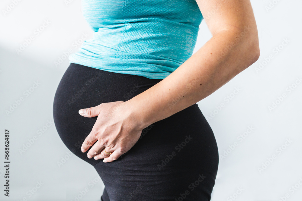 pregnant woman touching her bump in the latest stage of pregnancy, mid ...