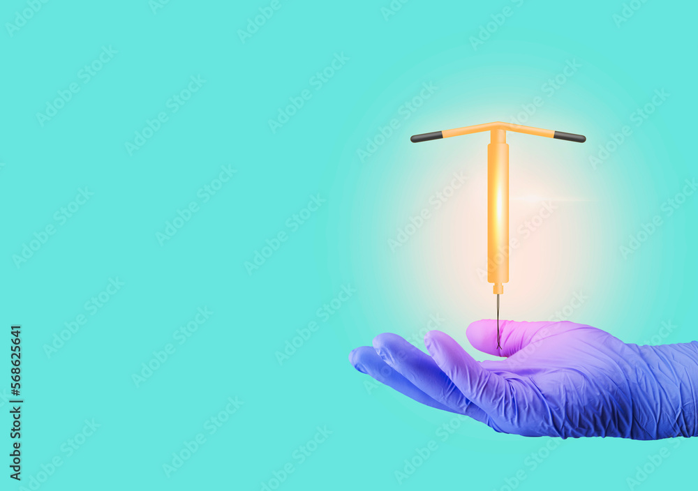hand holding a T-shaped birth control intrauterine device, IUD. copper ...