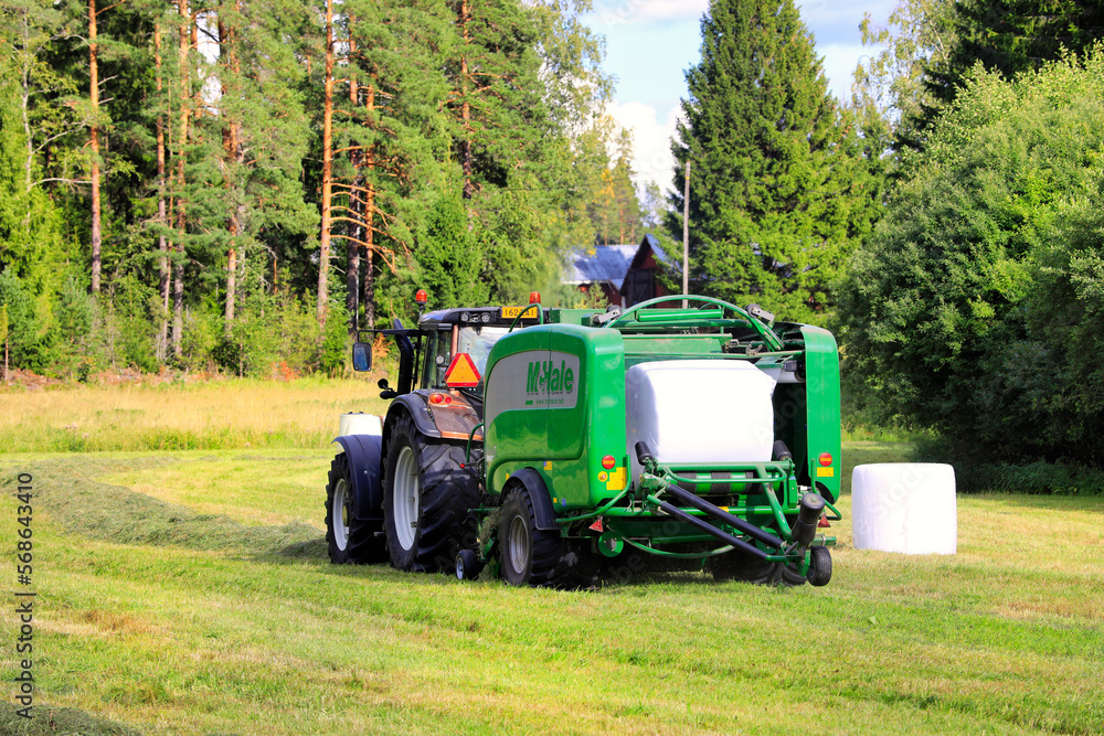 Farmer working in hay field with Valtra tractor and McHale 3 plus ...