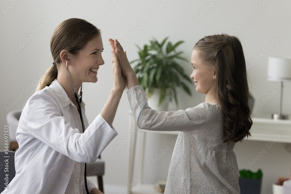Cheerful pediatrician woman giving high five to little patient girl ... Cheerful pediatrician woman giving high five to little patient girl ...