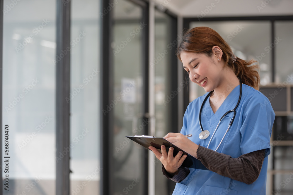 Female doctor filling up a medical form on a clipboard while standing ...
