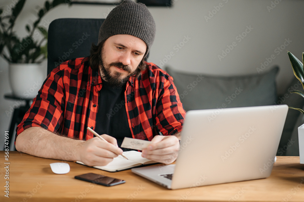 Student taking notes down from his new laptop computer while browsing ...